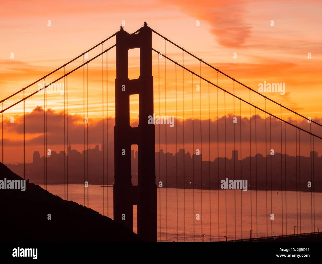 The Golden Gate Bridge during dramatic sunset with cityscape silhouette in the background Stock ...