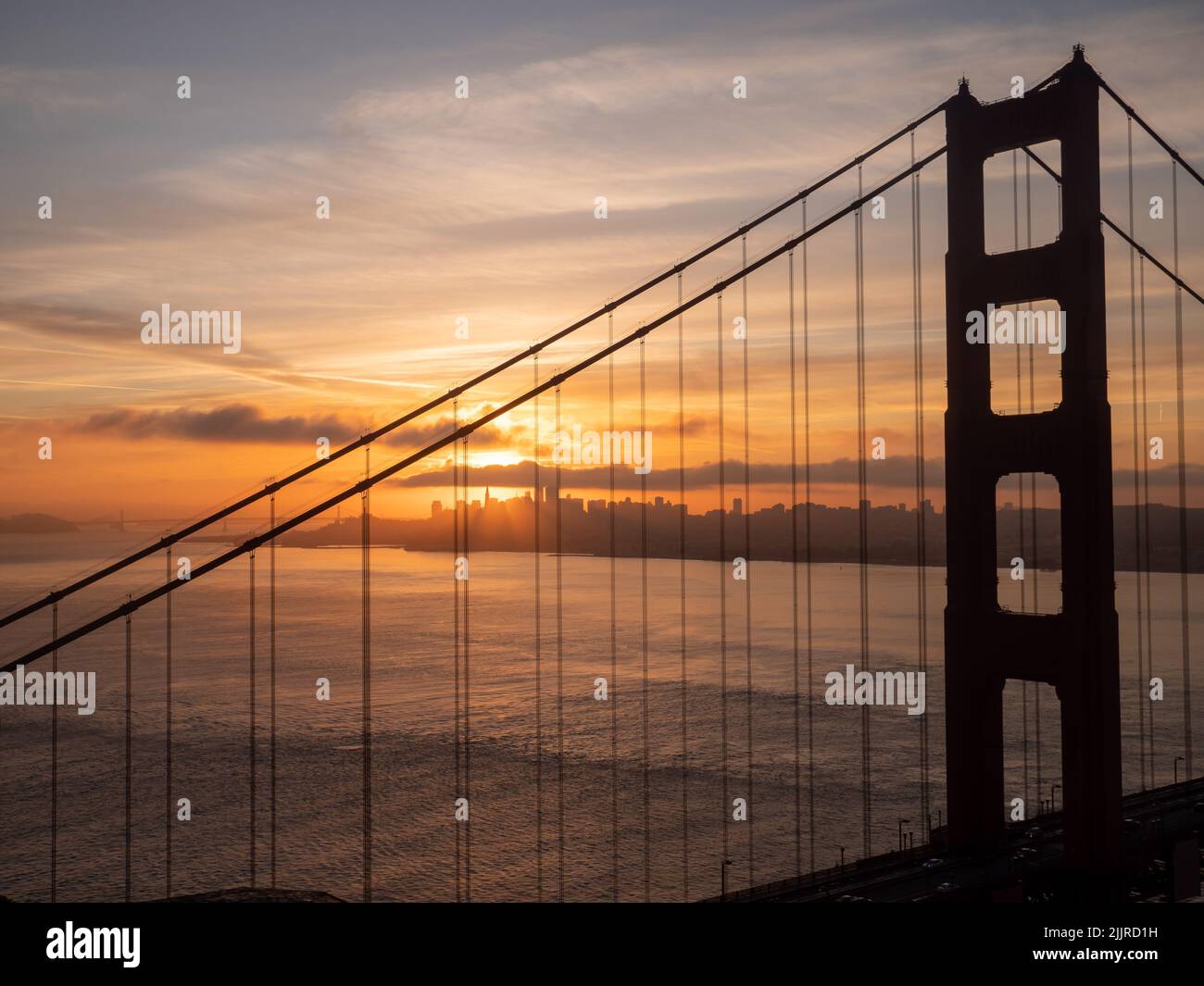 The Golden Gate Bridge during dramatic sunset with cityscape silhouette in the background Stock ...