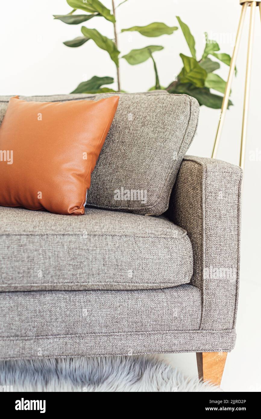 A vertical of a grey couch with a grey and a brown leather pillows on ...