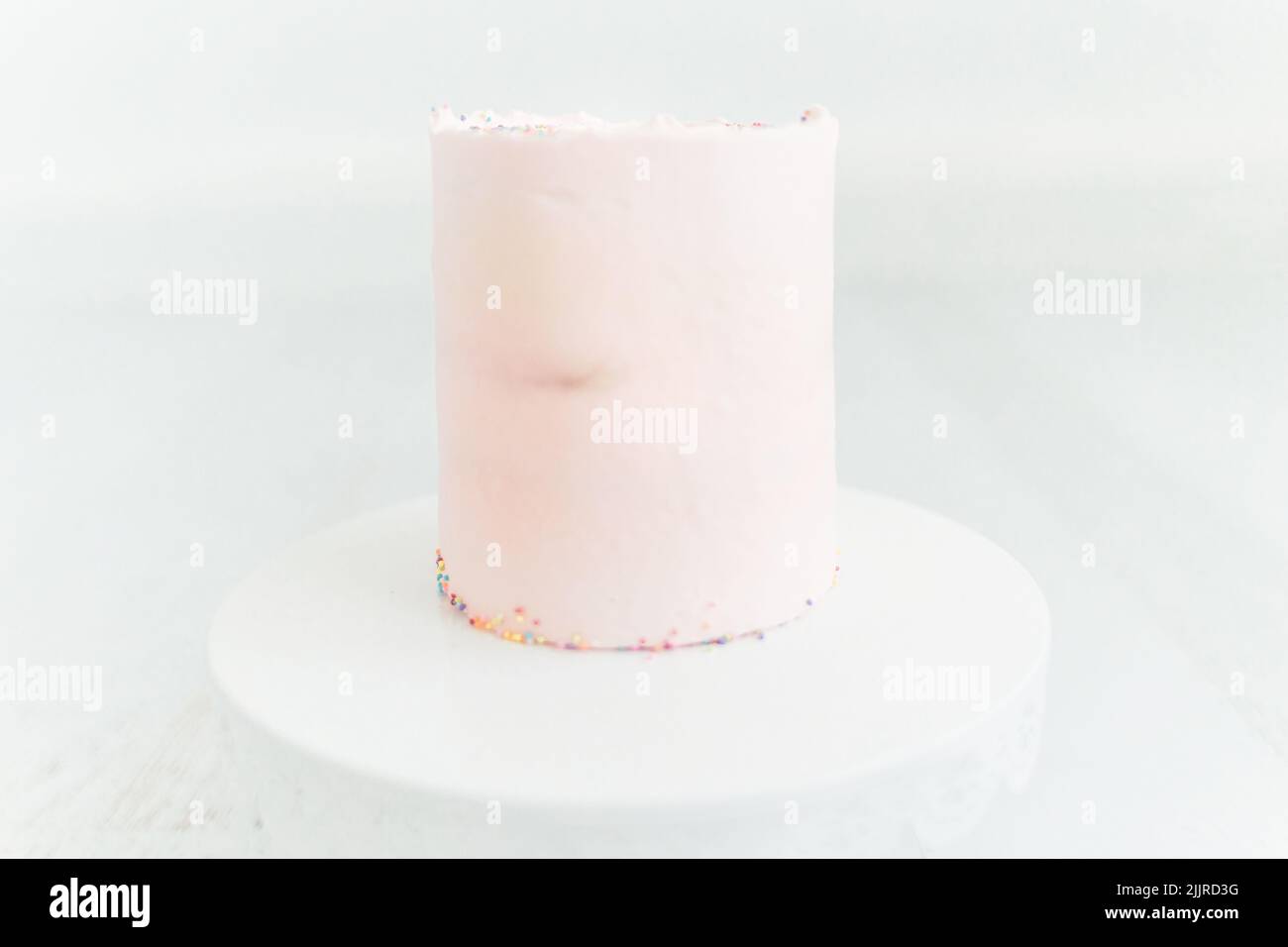 A side view of a light pink cake on a stand on white background Stock ...