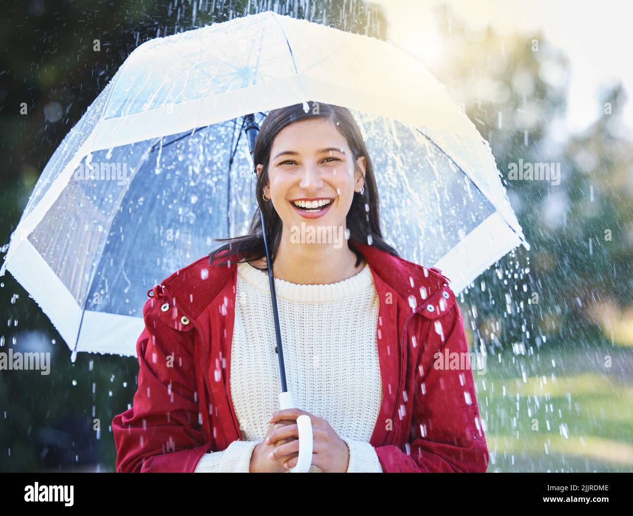 The rain cant get me now. a young woman holding an umbrella in the rain ...