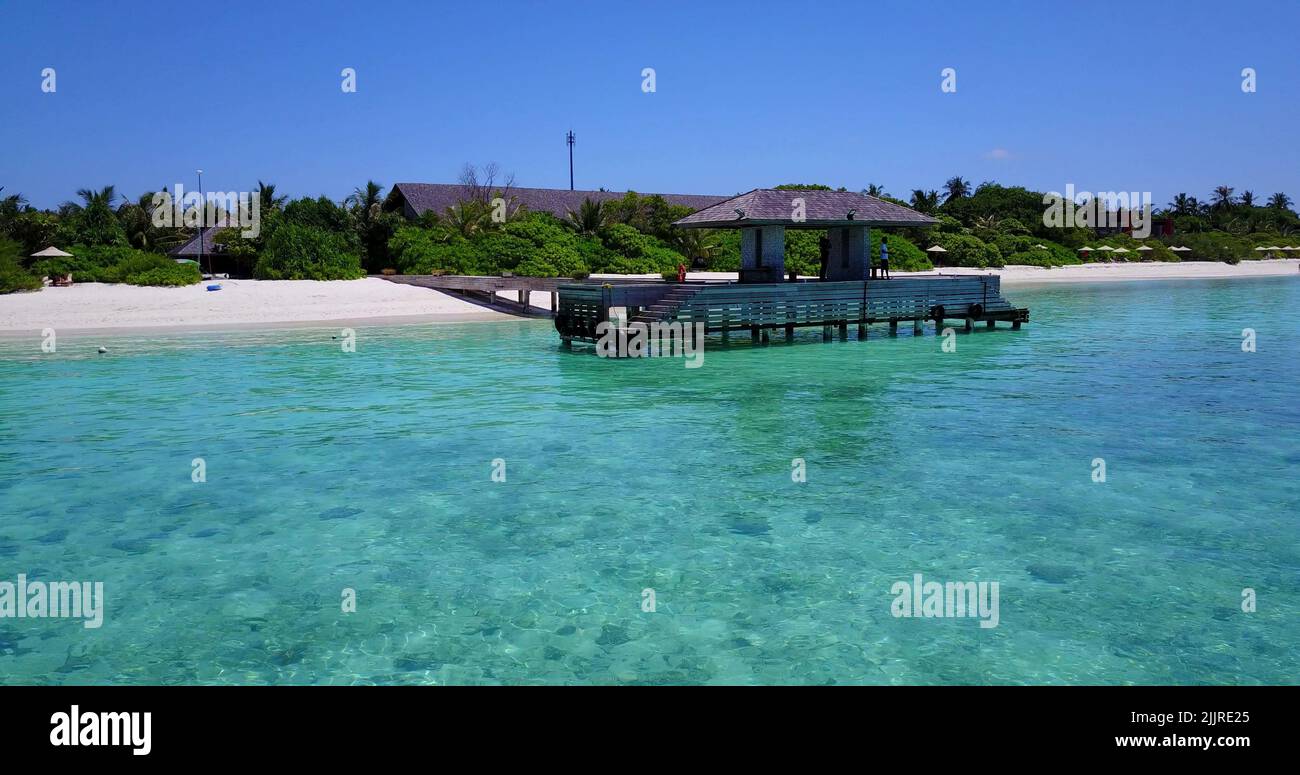 An aerial view of covered jetty on sea surrounded by emerald water in ...