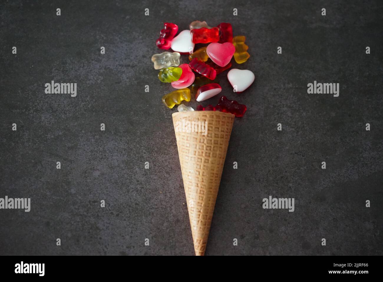 The colorful gummy bears and the hearts by the waffle cone on a black ...