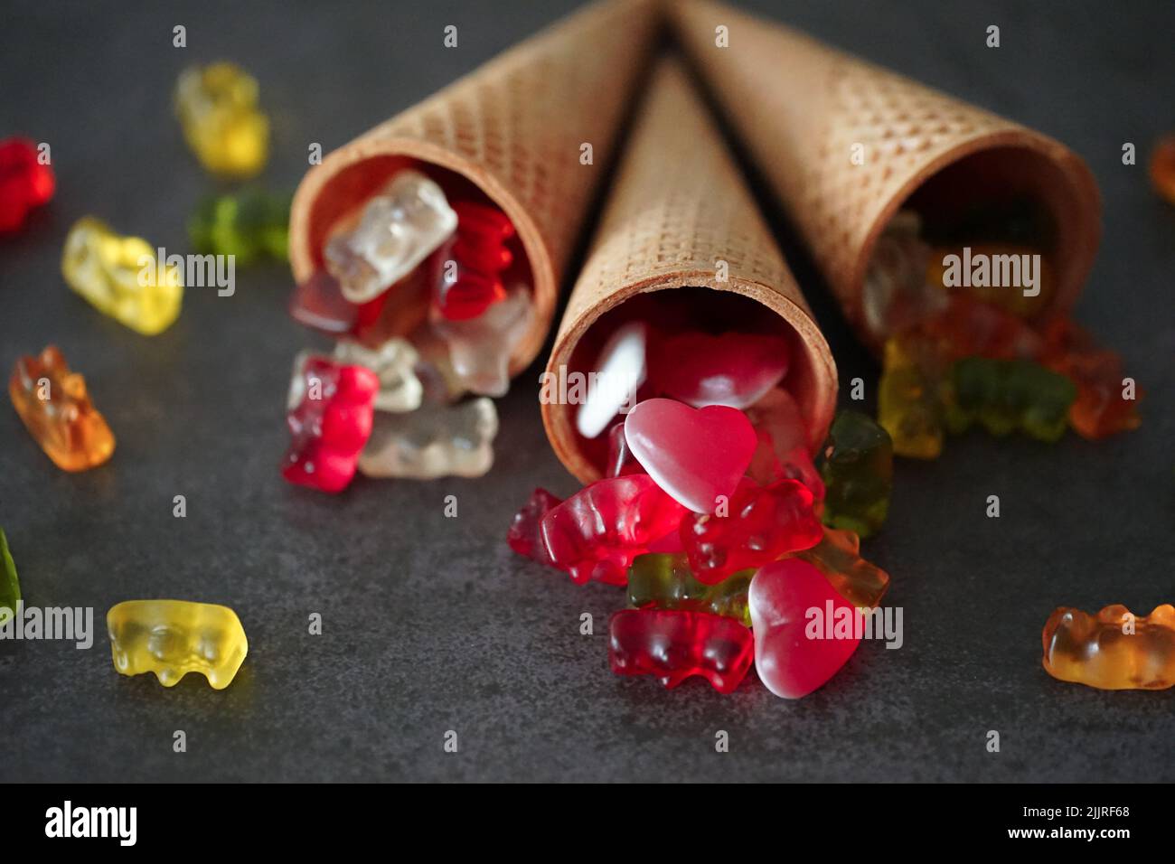 The colorful gummy bears and the hearts by the waffle cones on a black ...