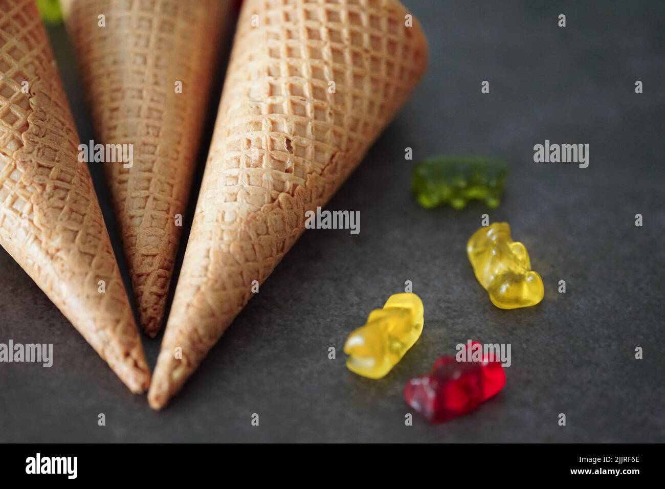 The colorful gummy bears and the hearts by the waffle cones on a black ...