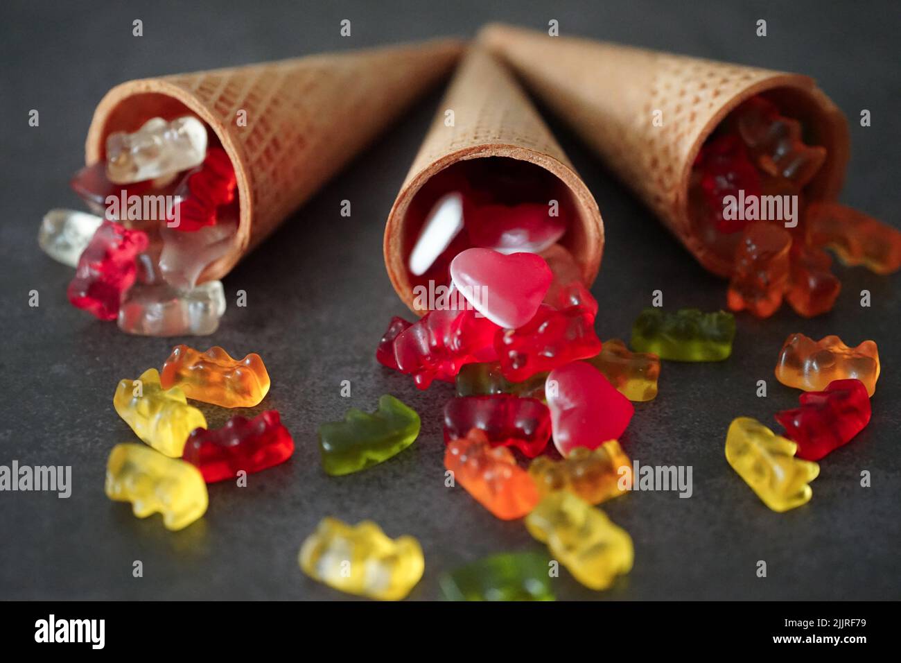 The colorful gummy bears and the hearts by the waffle cones on a black ...