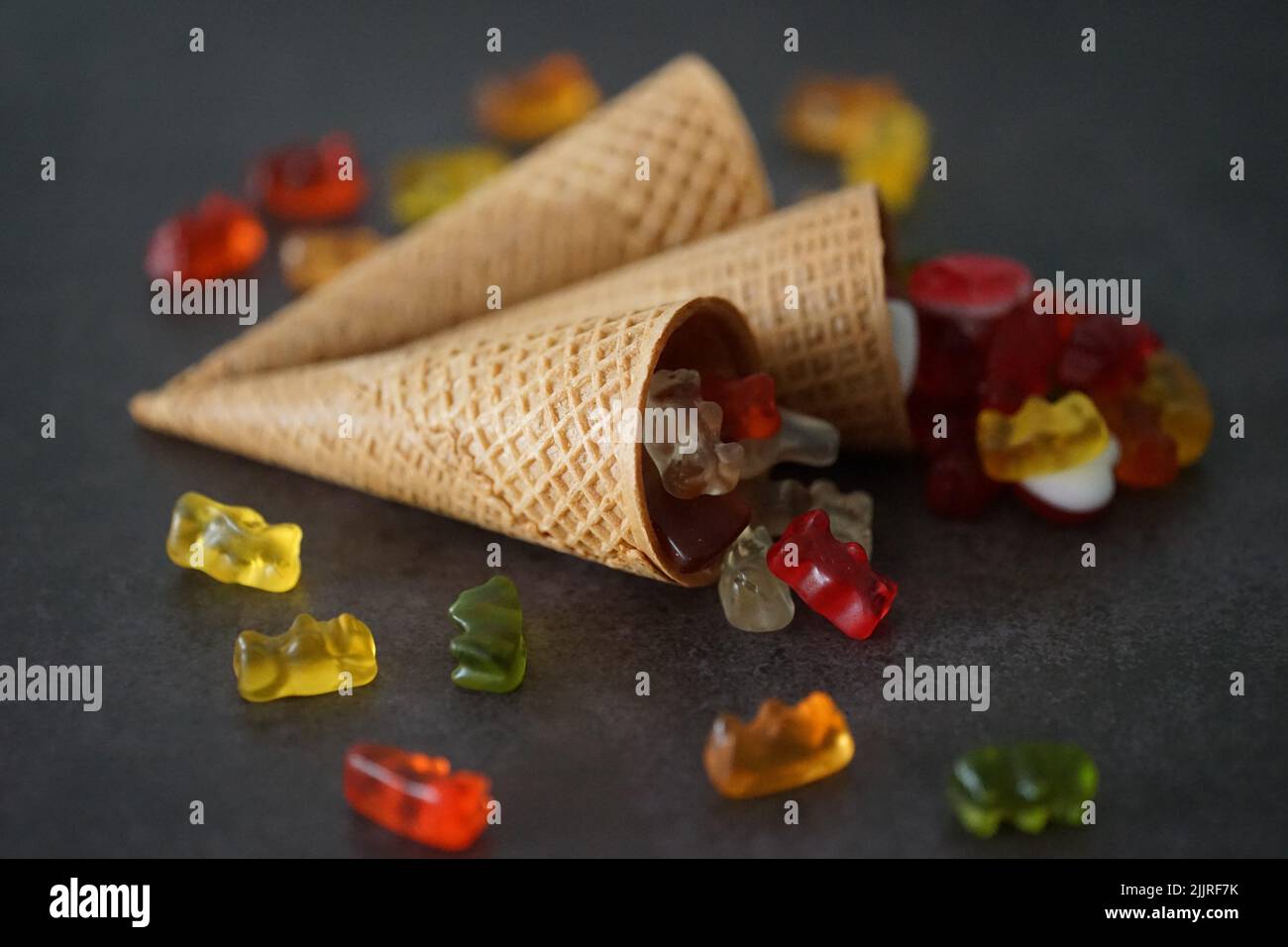 The colorful gummy bears and the hearts by the waffle cones on a black ...