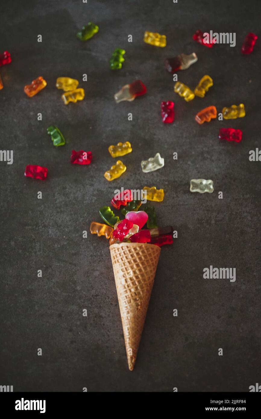 A vertical closeup of an ice cream cone with gummy bears and heart ...