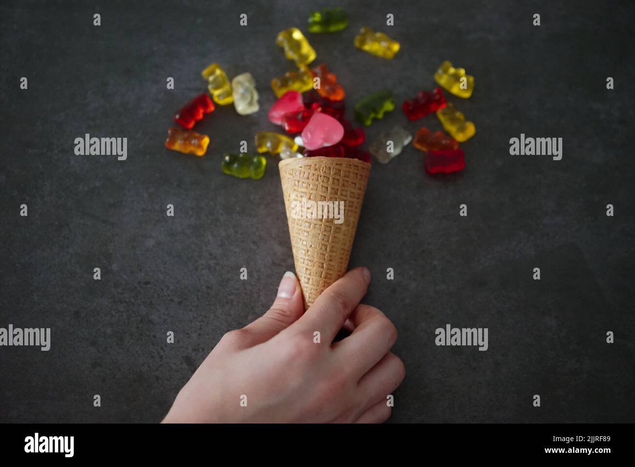 A closeup of an ice cream cone with gummy bears and heart jellies on ...