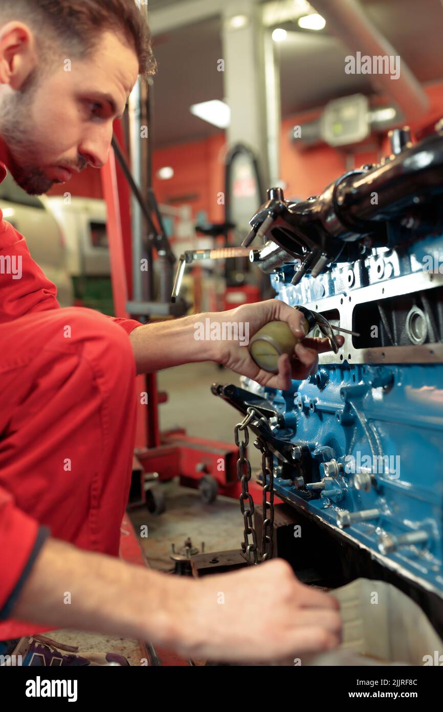 A vertical shot of a mechanic in a red uniform mounting the C engine ...