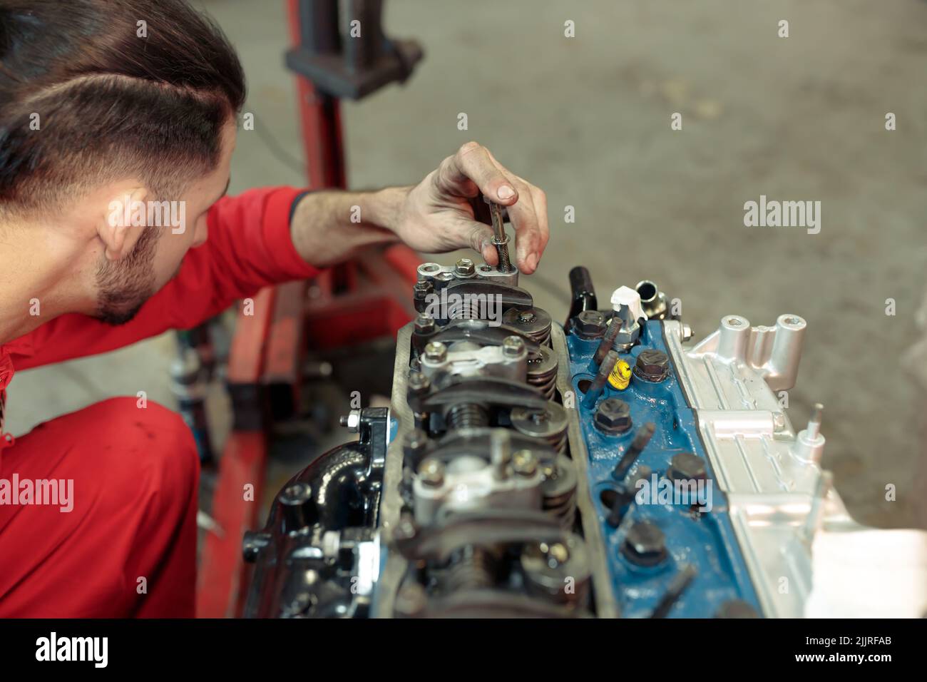 A young Caucasian mechanic mounting the car engine Stock Photo - Alamy