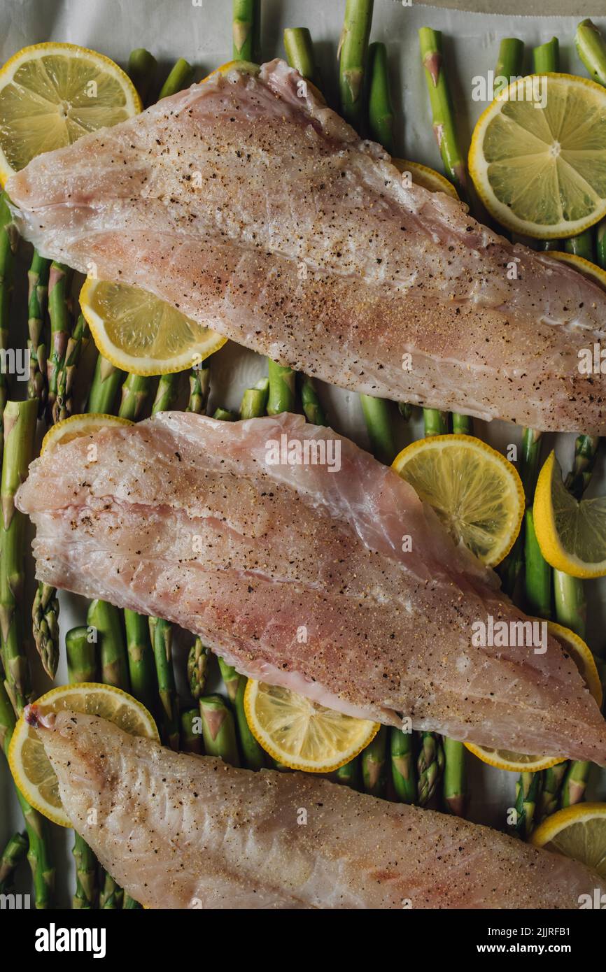 Raw pacific rockfish on a bed of asparagus and lemon wheels, sheet pan ...