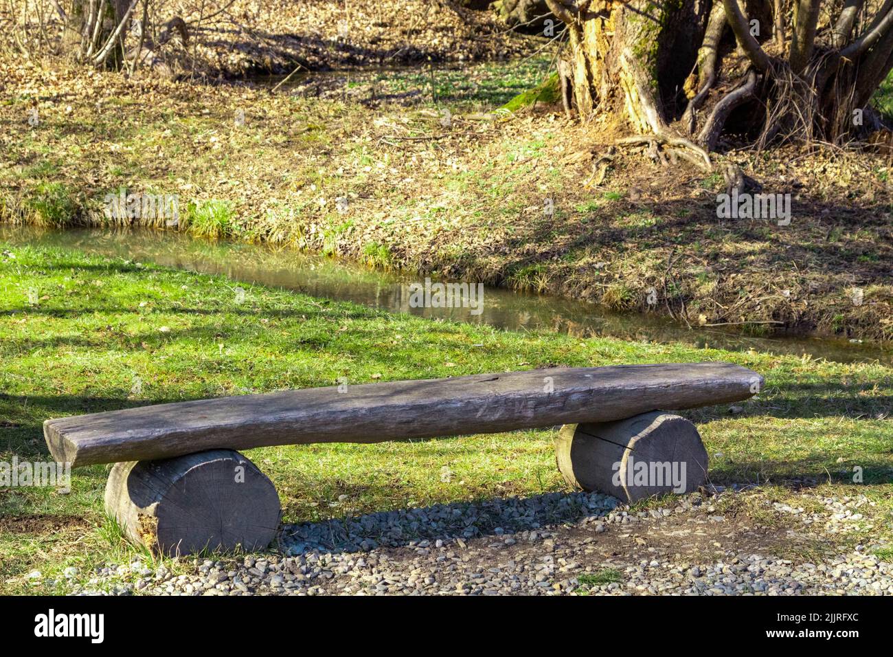 A wooden bench made of a board and logs in the forest with a small ...