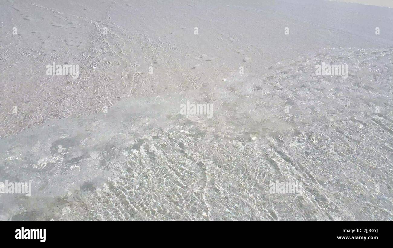 A beautiful view of transparent water hitting the sandy shore of ...