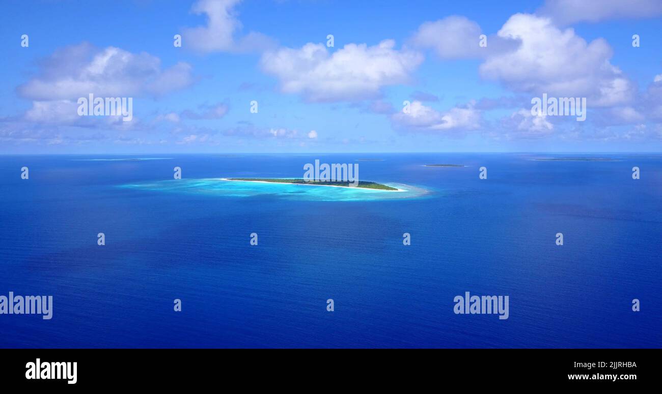 An aerial drone shot of an untouched island in the Maldives washed by ...