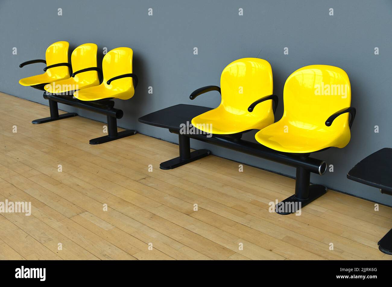 Some empty yellow seats on a gray wall in a waiting room Stock Photo ...