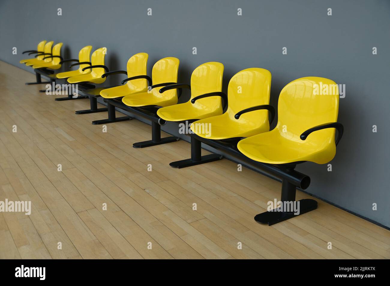 Some empty yellow seats on a gray wall in a waiting room Stock Photo ...