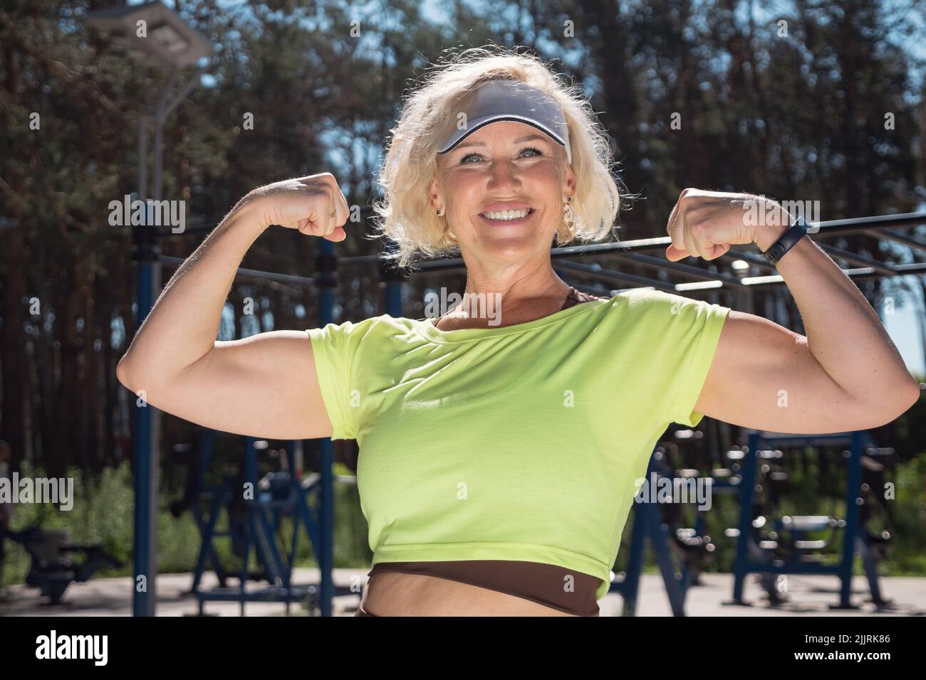 Mature woman shows powerful arm biceps against sports ground Stock ...