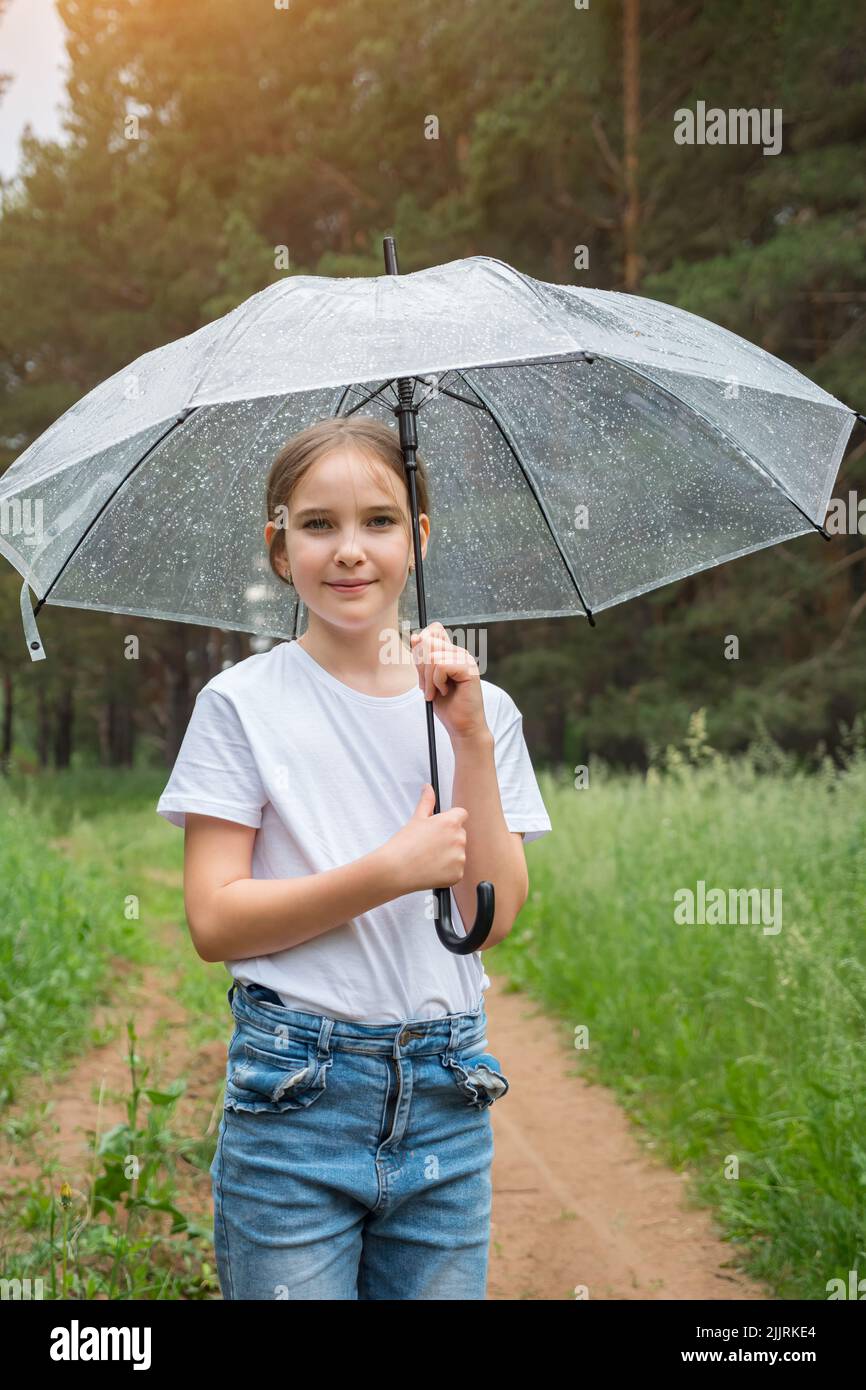 Girl holds umbrella hiding from rain during walk in forest Stock Photo ...