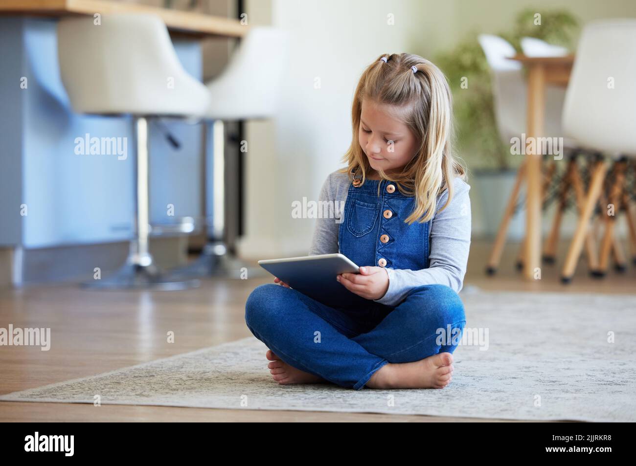 Learning about technology. a little girl using a digital tablet at home ...