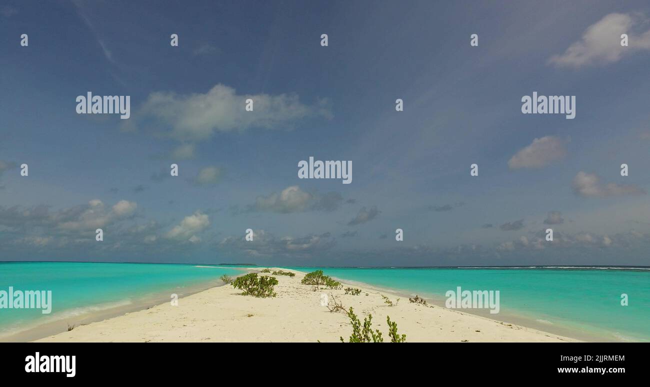 A beautiful shot of a narrow sandy island in the middle of an azure ...