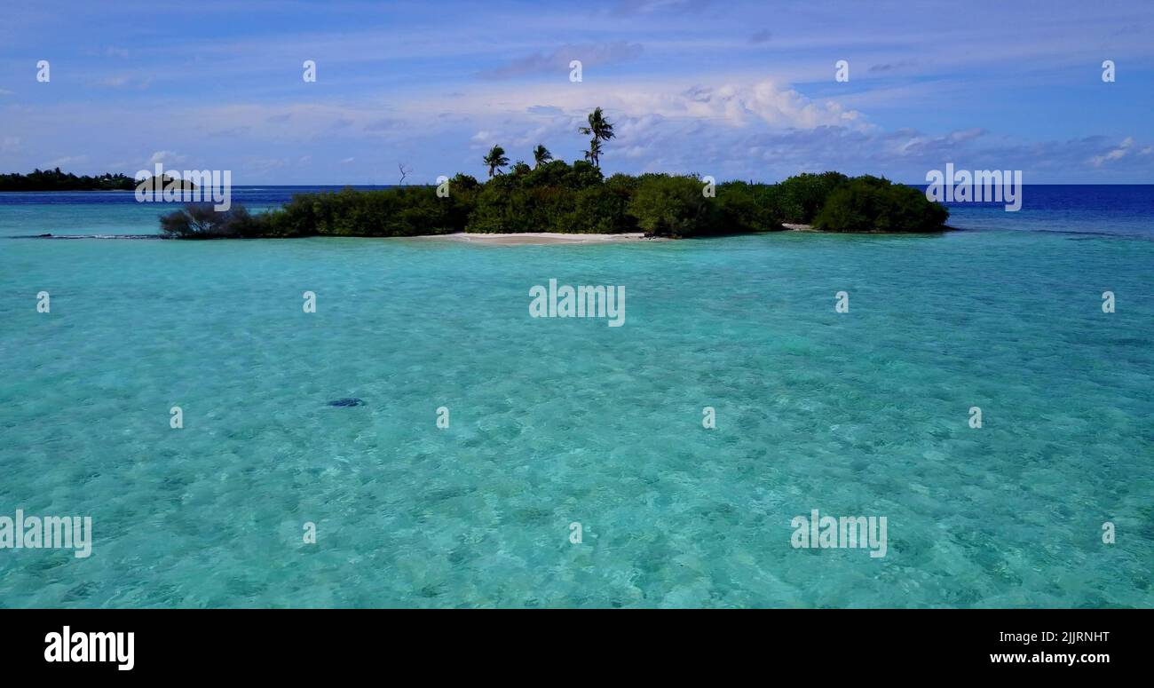 An aerial view of the azure water of the ocean and a green island in ...