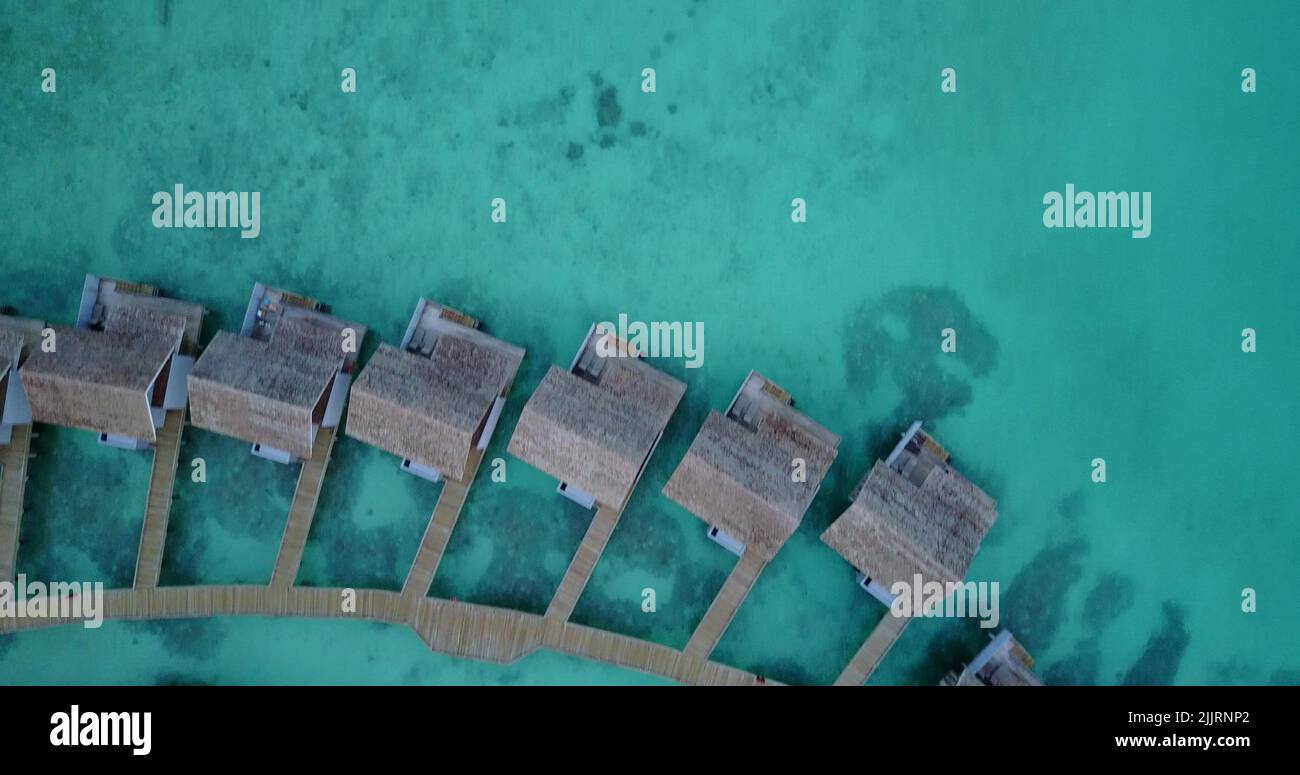 A bird's eye view of the azure water of the ocean and wooden huts in ...