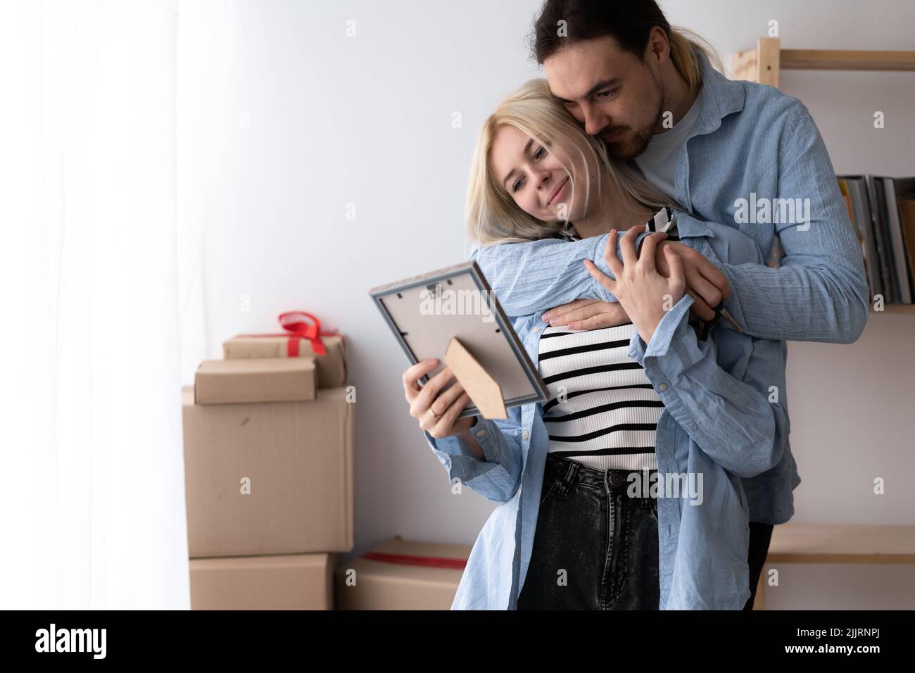 Happy wife and husband looking at photo frame, sharing memories ...