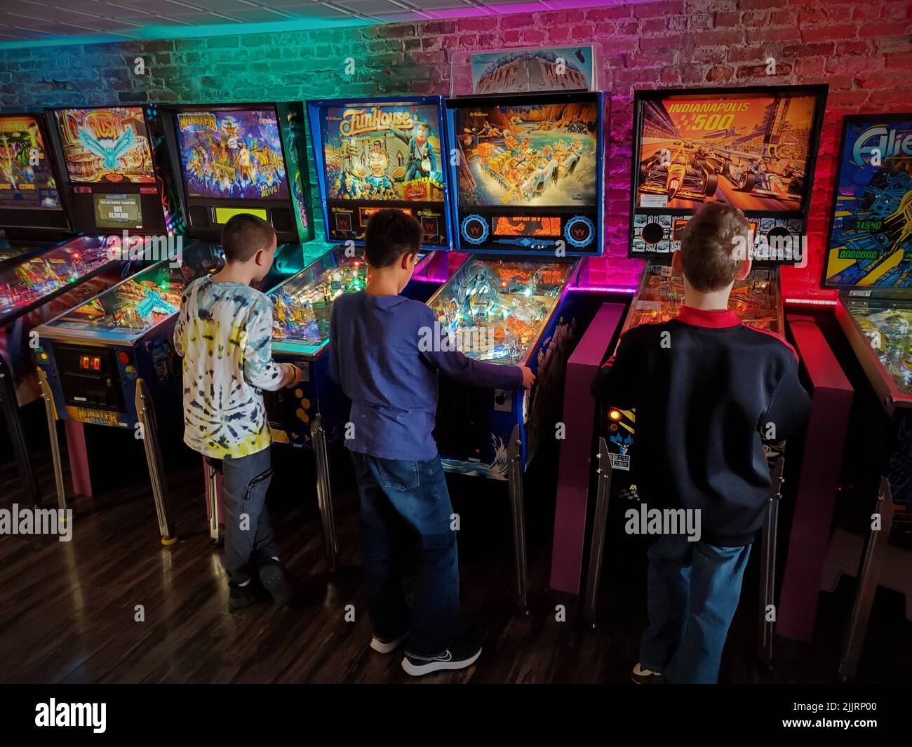 A boys play pinball machines in an entertainment center with colorful ...