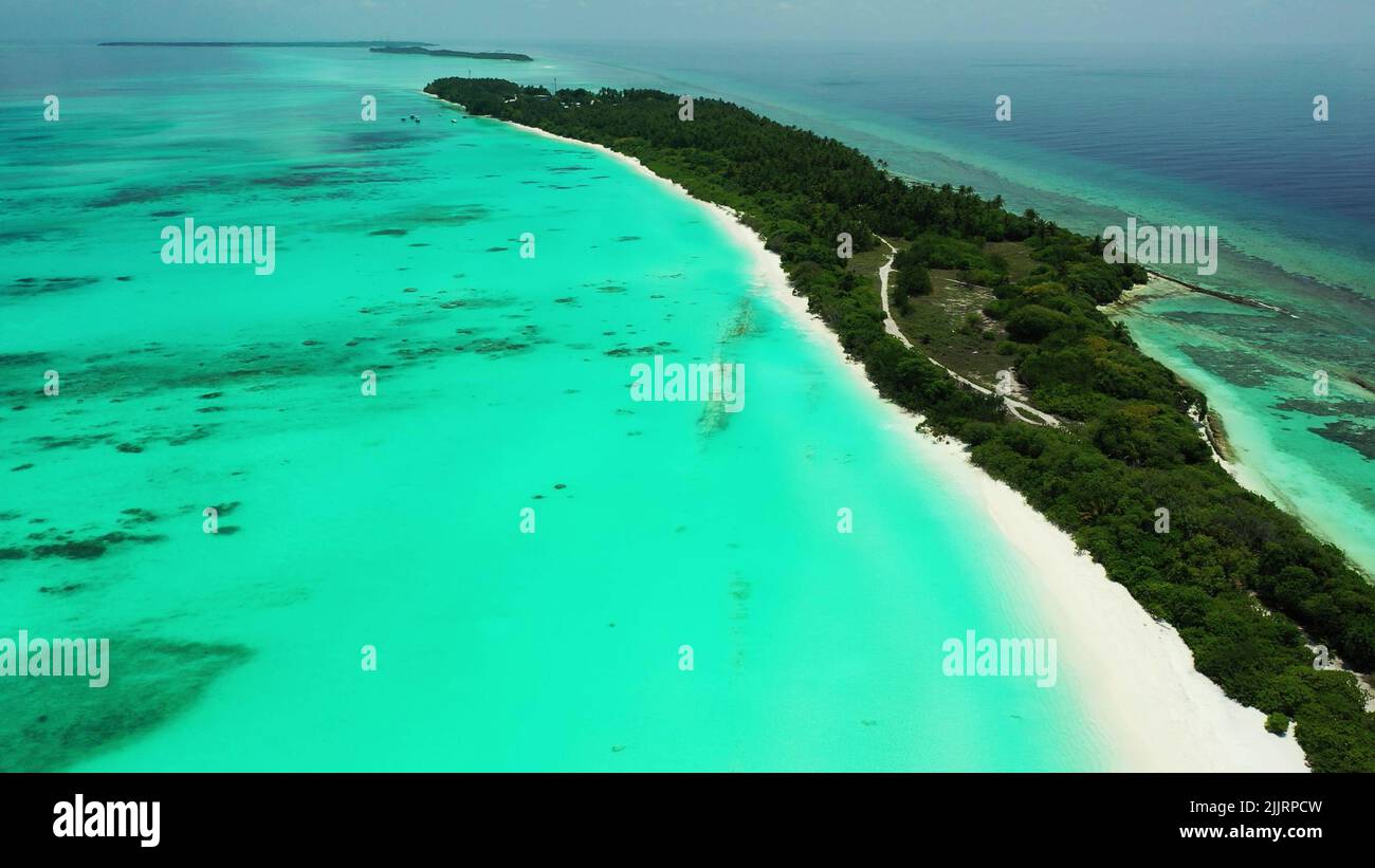 A drone shot of a green island with turquoise water in The Maldives ...