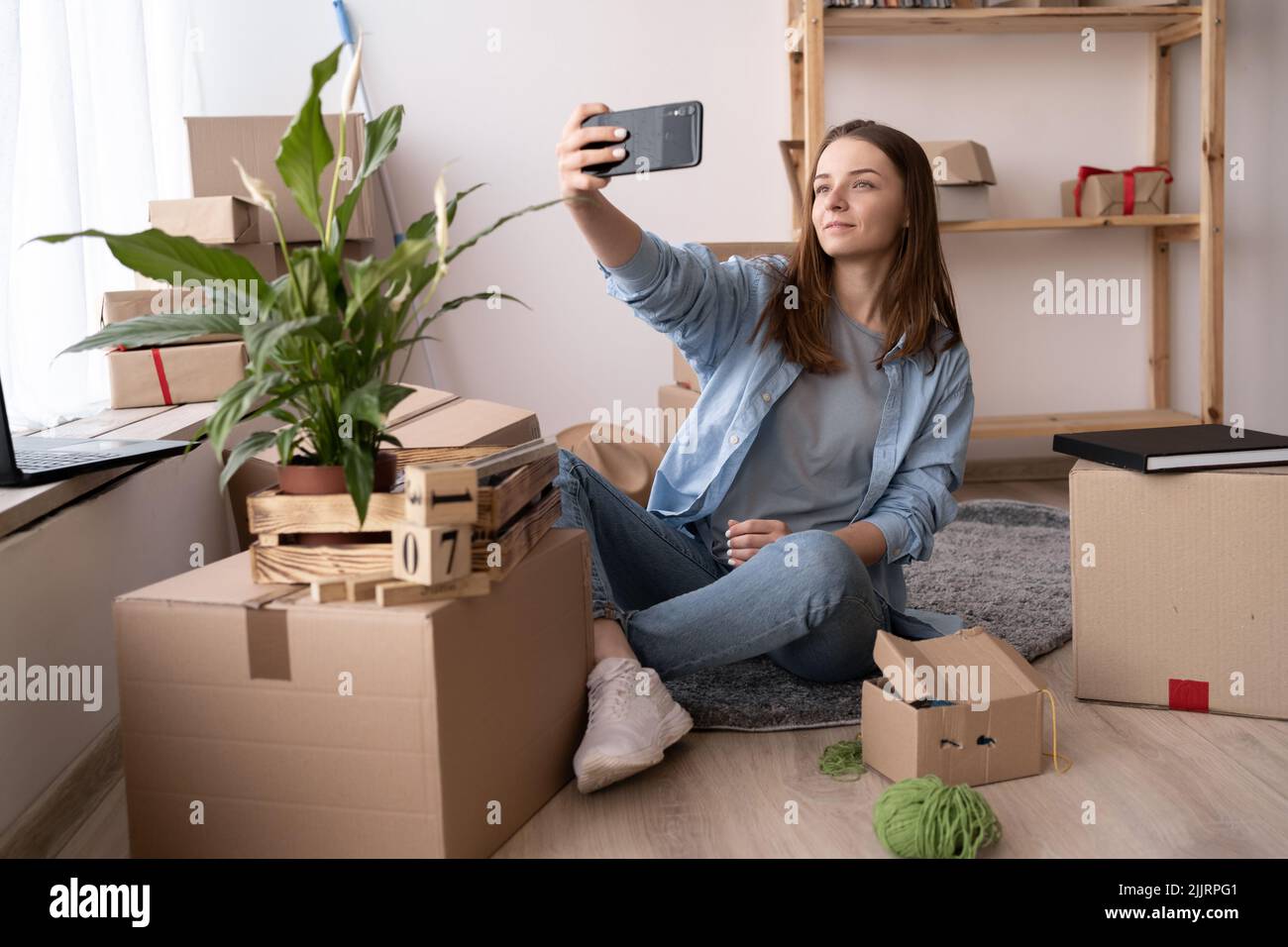 happy girl taking selfie with smartphone and sitting on floor among ...
