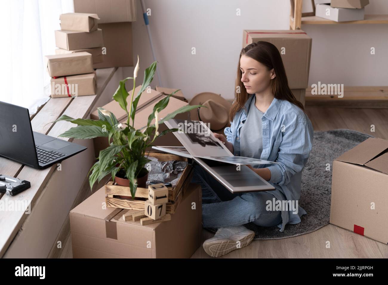 young caucasian woman is sad sitting on the floor looking at a photo ...