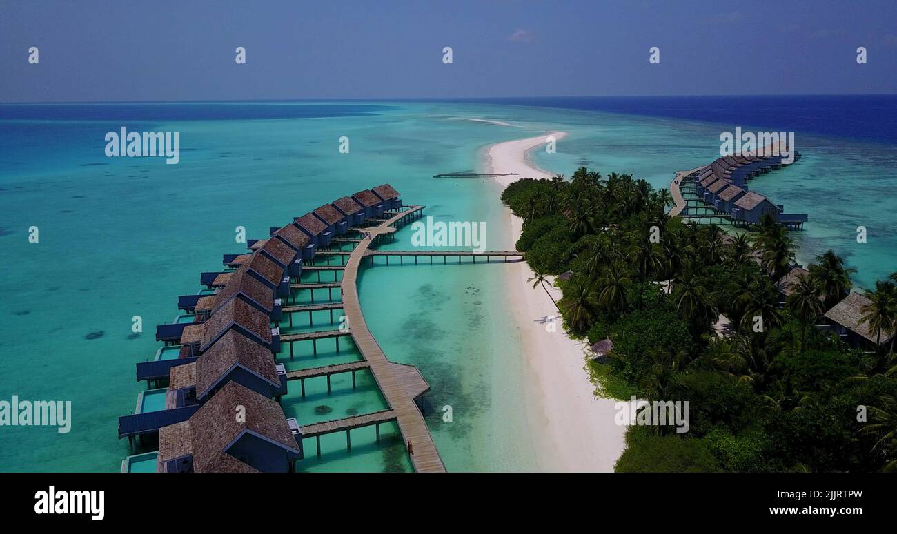 An aerial view of a beautiful island with overwater bungalows and palm ...
