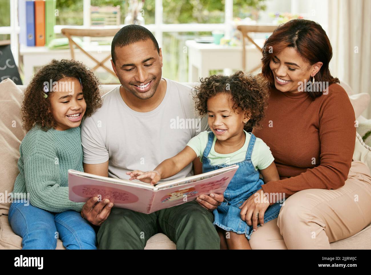 Always make time for family. a young family reading a book at home ...