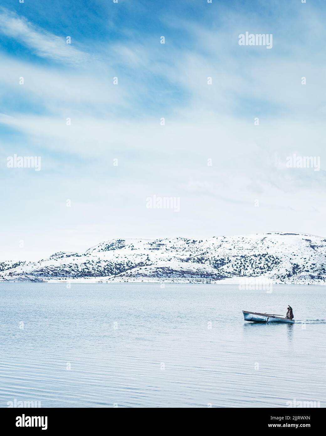 A vertical of a fisherman sailing on a boat in the Sevan Lake, Armenia ...