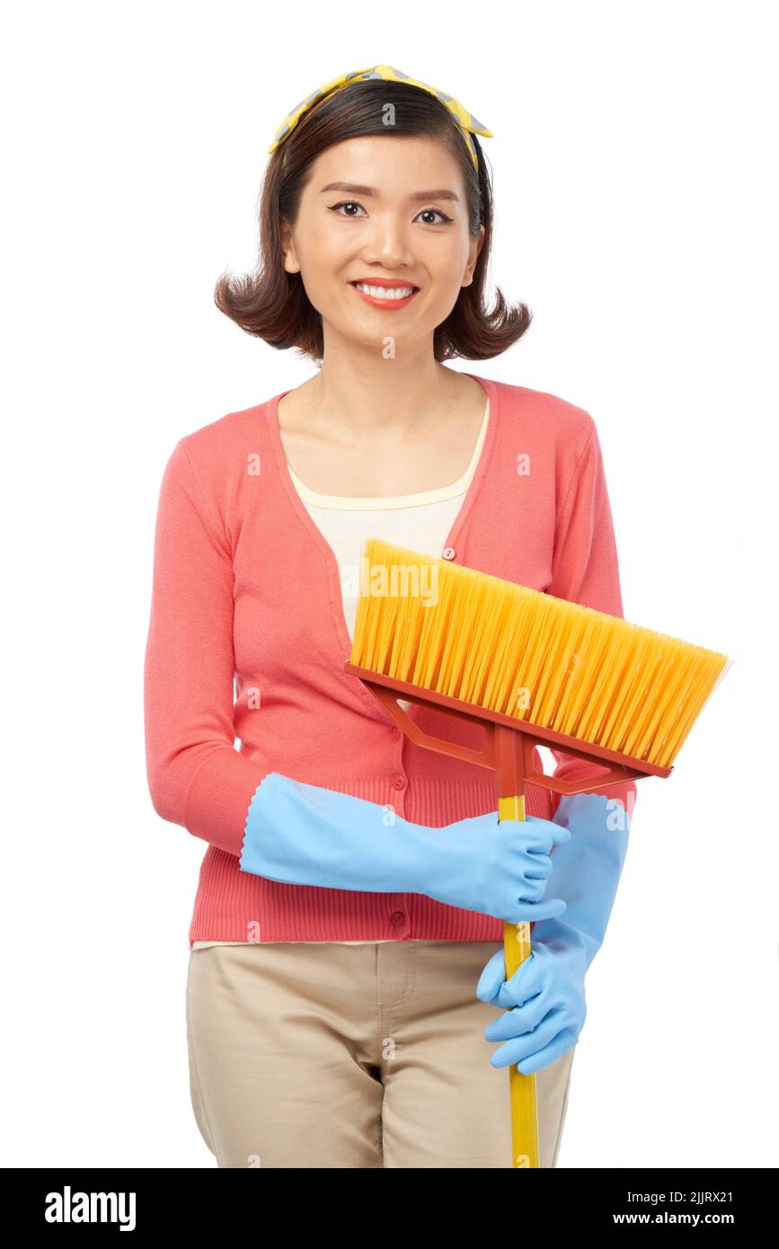Portrait shot of beautiful Asian woman with broom in hands distracted from sweeping floor in ...
