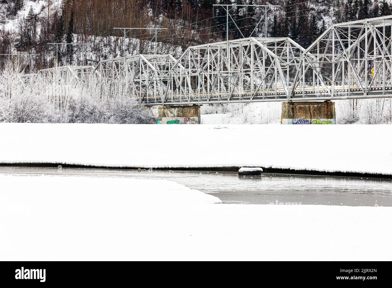A view of an old abandoned steel girder bridge covered with snow near ...