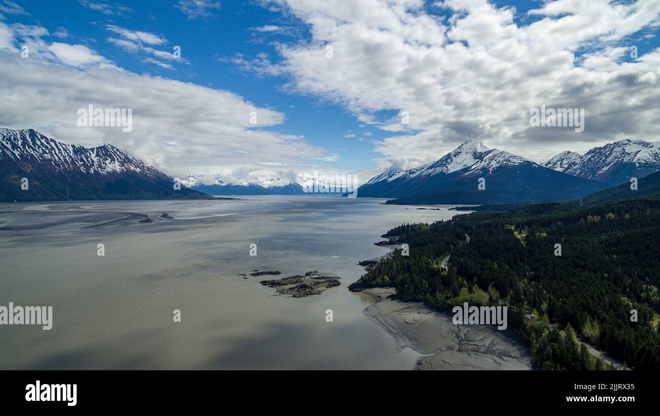 An aerial view of a snowy mountain range covered with clouds against a ...