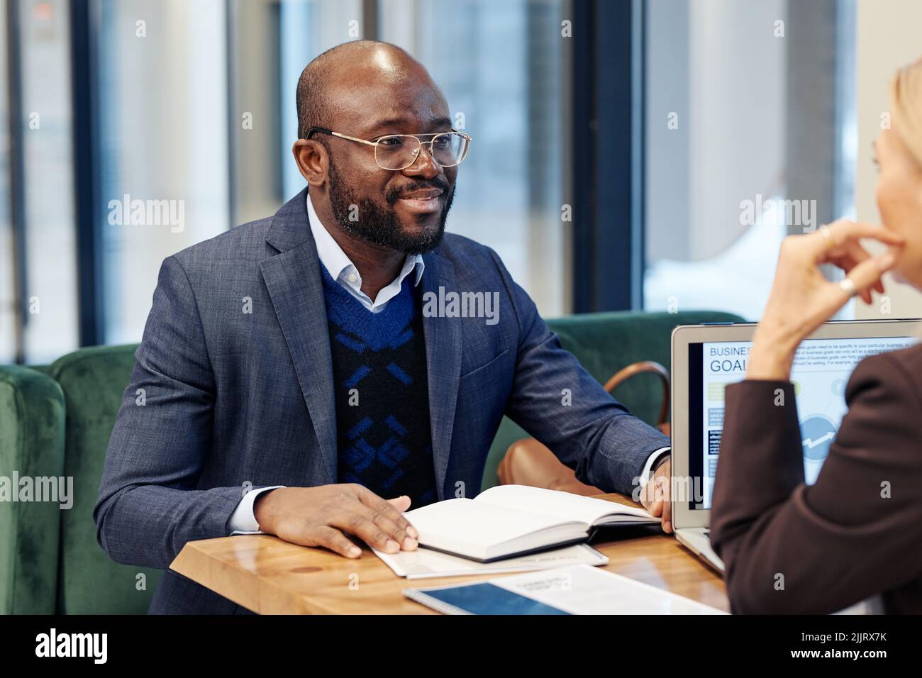 African successful lawyer listening to his client while they sitting at ...