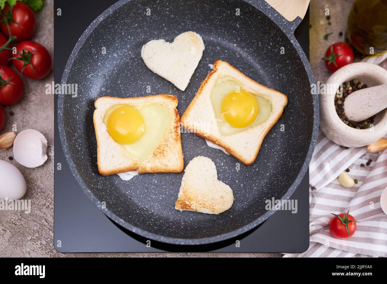 Fried egg Toasts with heart shaped holes on frying pan Stock Photo - Alamy