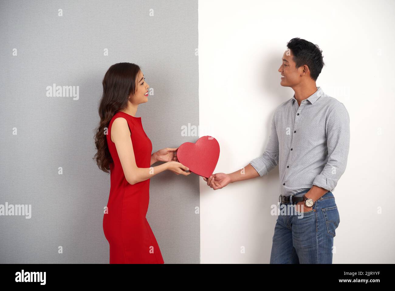 Profile view of joyful Asian boyfriend and girlfriend looking at each ...