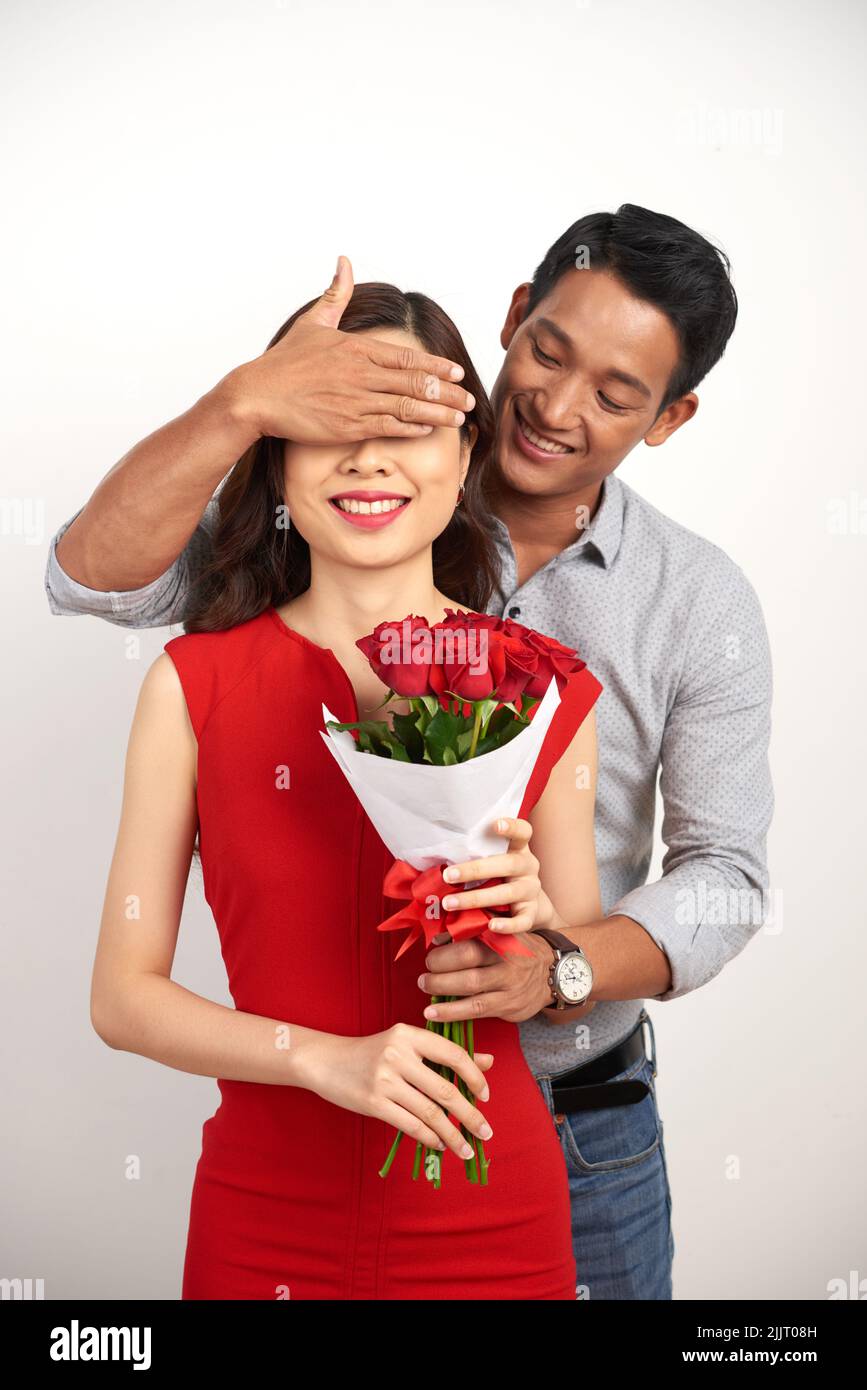 Handsome Asian man covering eyes of his smiling girlfriend with hand ...