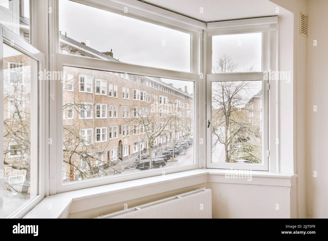 Plastic window and radiator on white wall in empty light room at home ...