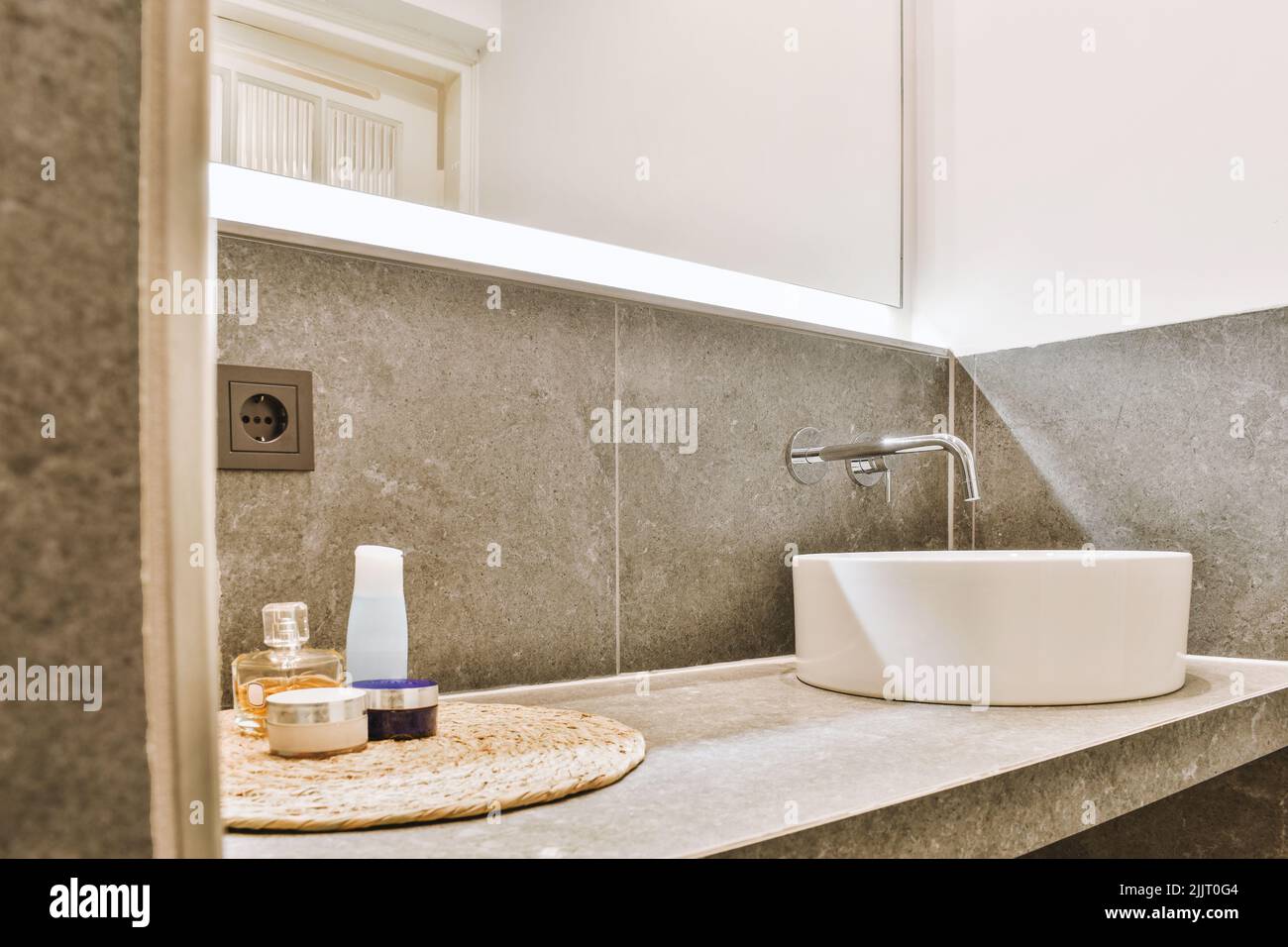 Sink with tap and liquid soap hanging on tiled wall under mirror in ...