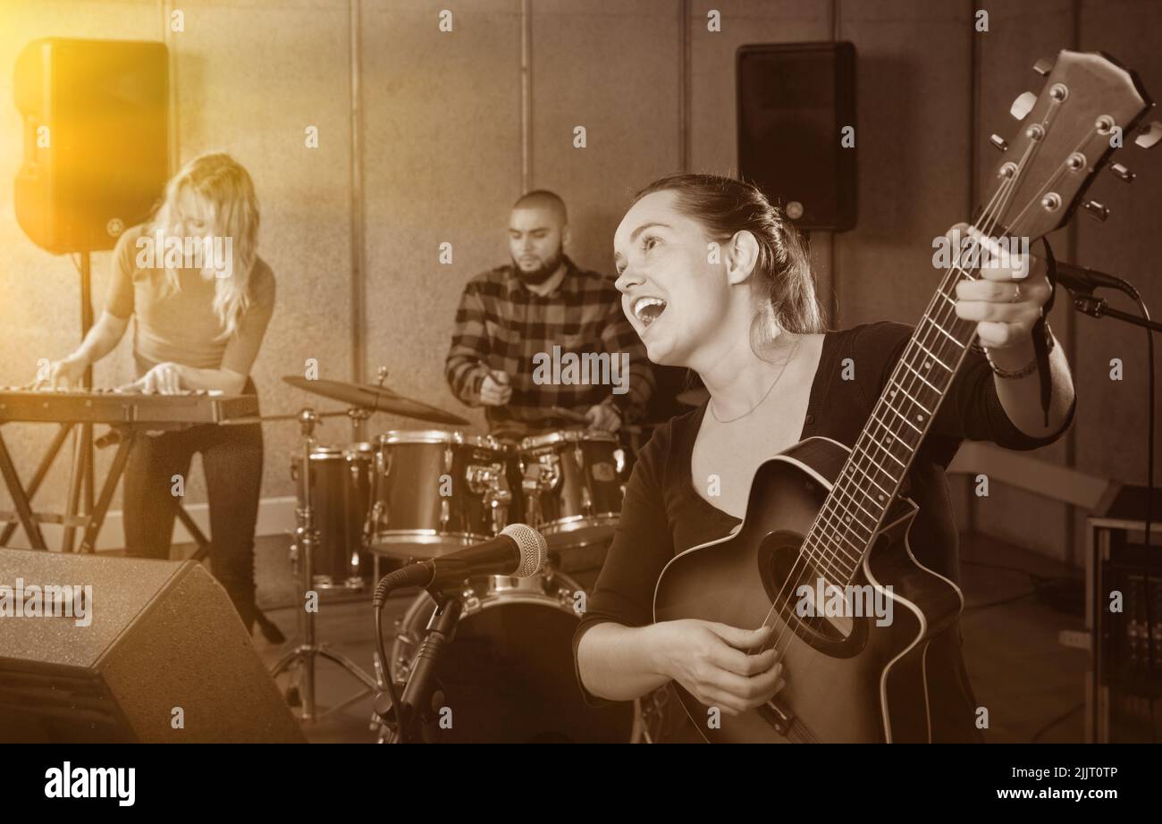 Attractive female soloist playing guitar and singing with her mu Stock ...