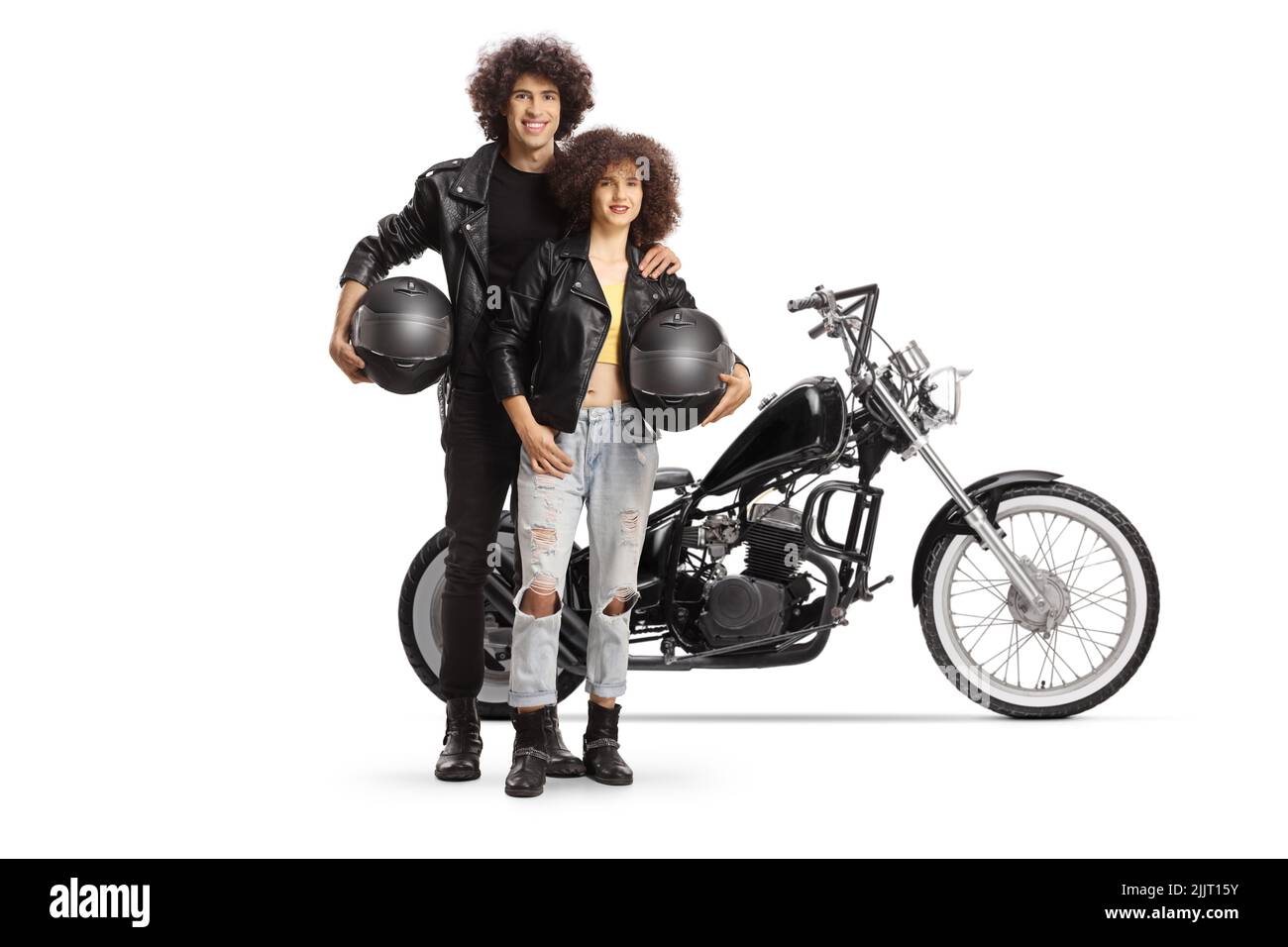 Full length portrait of a young couple in leather jackets with chopper holding motorbike helmets ...