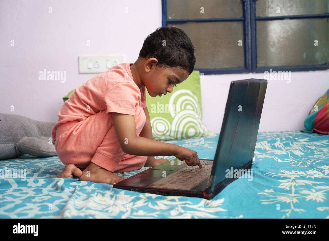 A beautiful shot of an Indian little kid playing with a computer on a ...