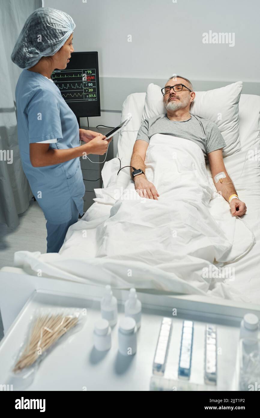 High angle shot of doctor holding digital tablet talking to mature man ...