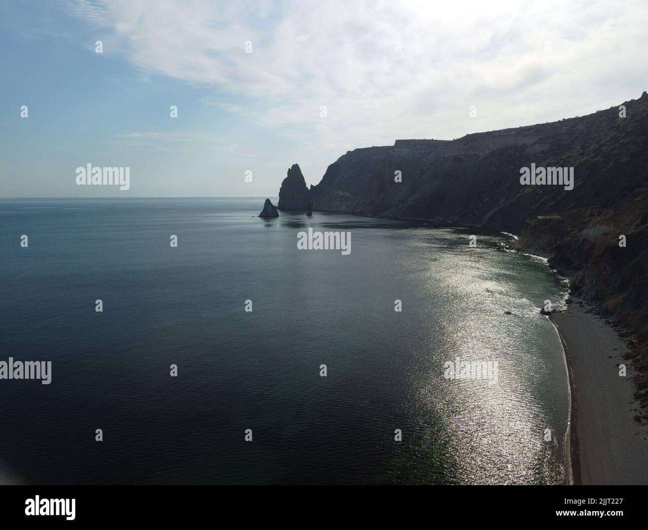 Aerial view on calm azure sea and volcanic rocky shores. Small waves on ...