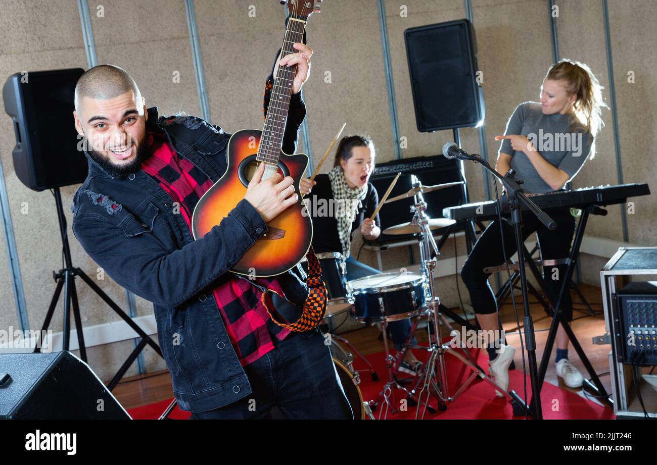 Guy guitar player and singer practicing with band members in recording ...